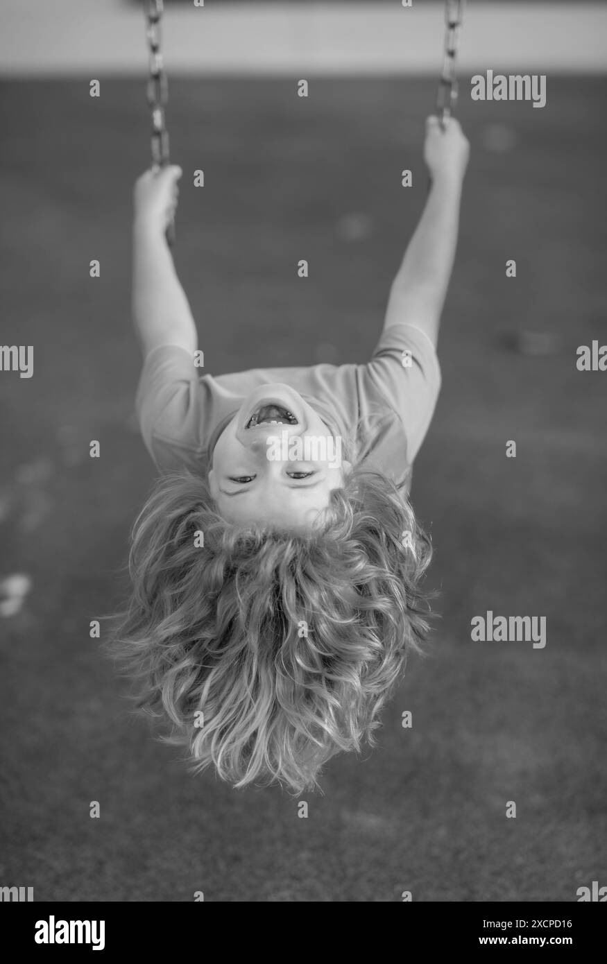 Child on swing playing on outdoor playground. Child boy exercise at playground. Cute kid having ...