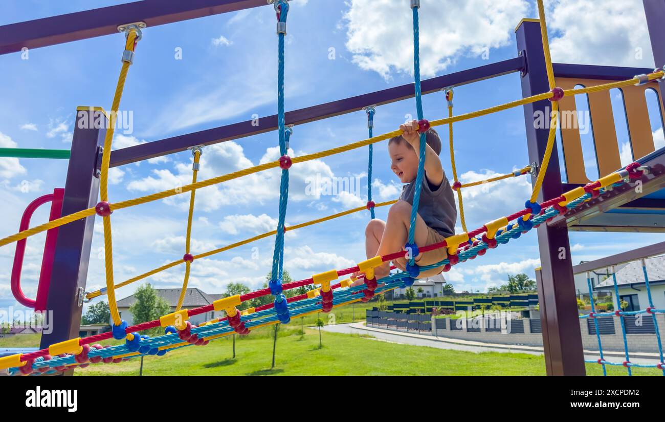 View from the ground on toddler boy walking over the rope bridge at ...