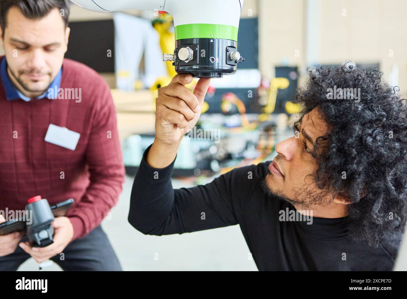 Two Engineers Collaborate On Programming And Inspecting A Robotic Arm