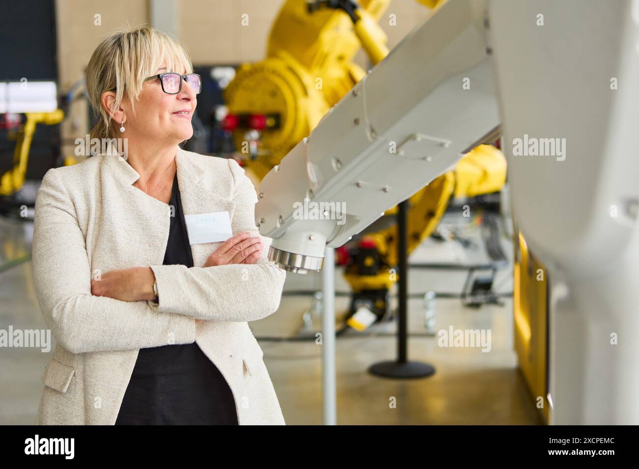 Woman observing an advanced robotic arm in a high-tech industrial ...