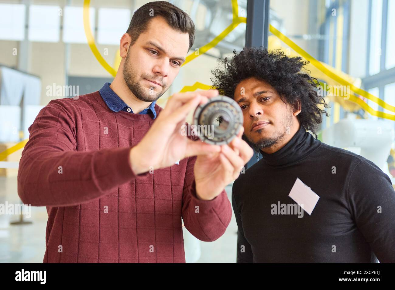 Two engineers closely examining a mechanical part, focusing on robotics, automation, and ...