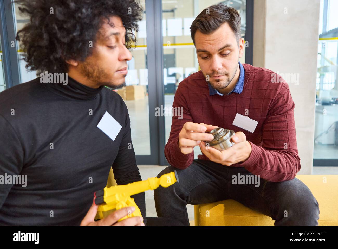 Two engineers discussing robotic components, closely examining parts to improve automation ...