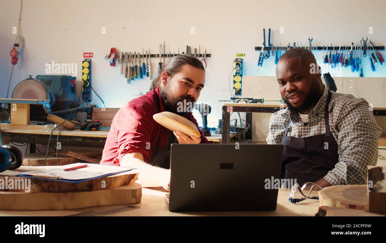 Carpenter and colleague verifying finished wood art product, comparing ...