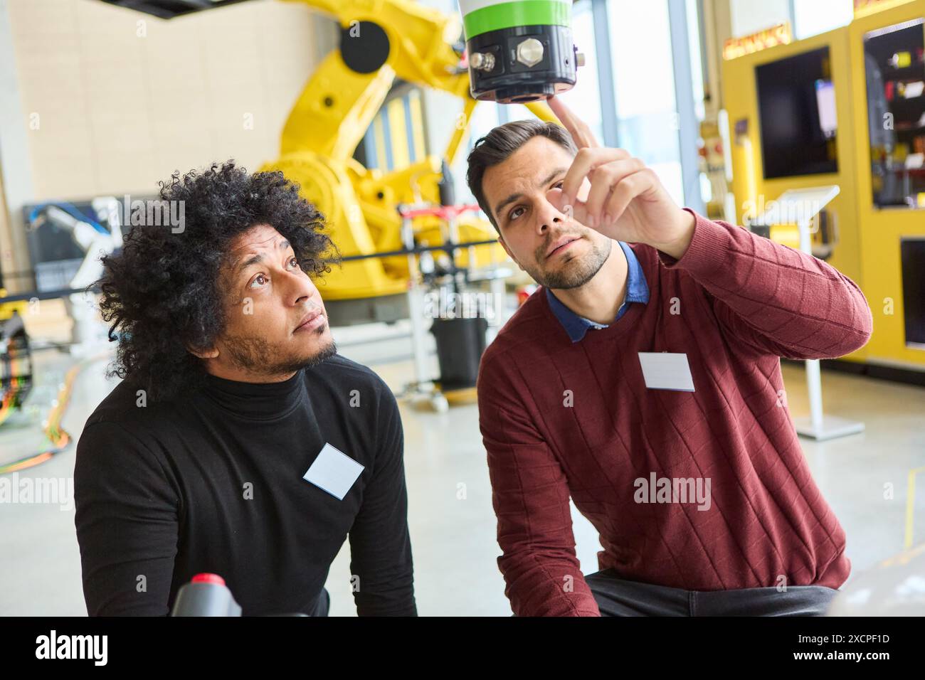 Two engineers analyze a robotic hand during a training session focused on industrial robotics ...