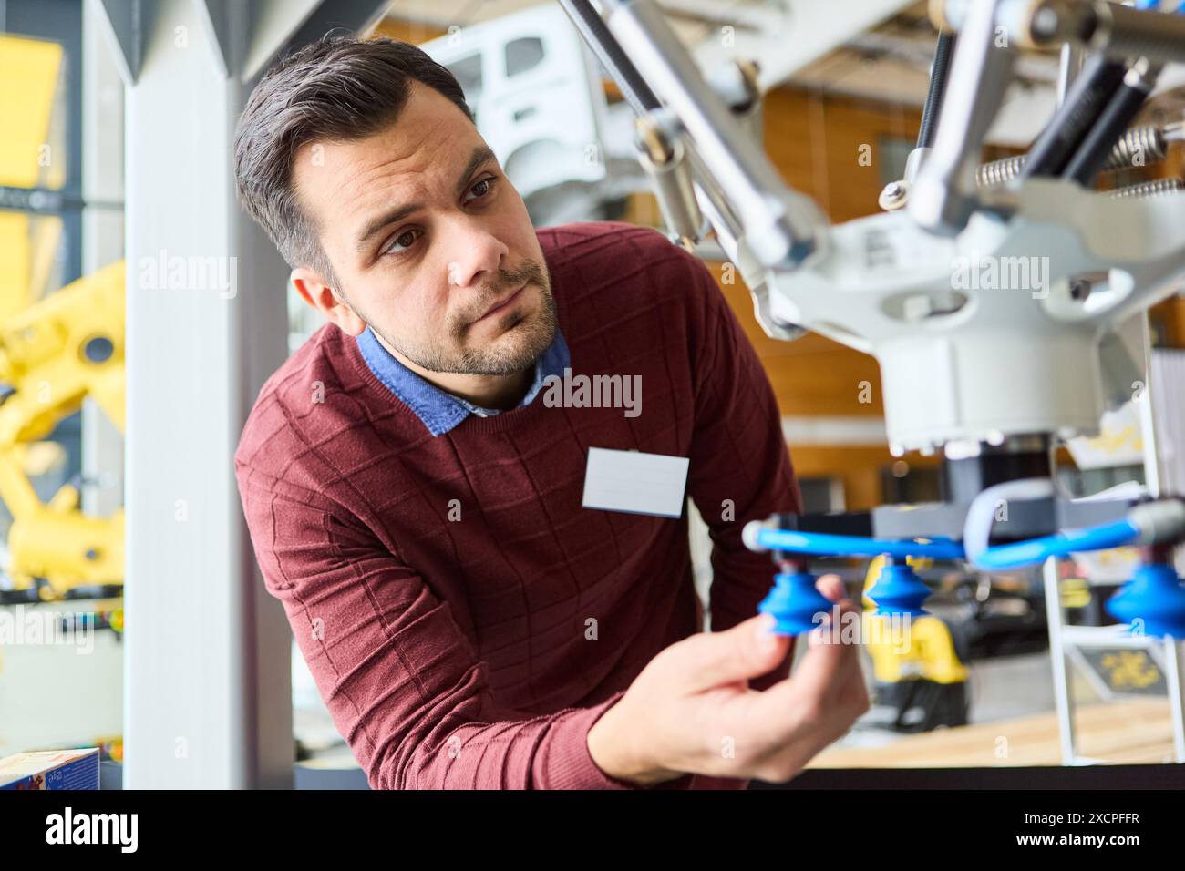 Engineer closely inspecting a robotic gripper arm in an industrial ...