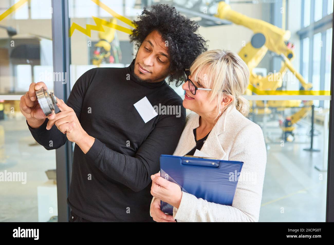 Two engineers discussing a robotics component in an industrial setting ...
