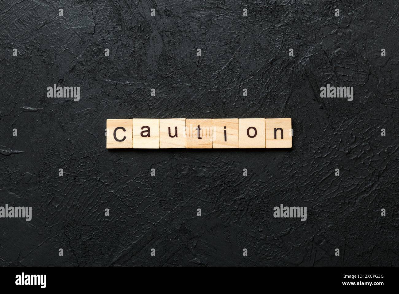 CAUTION word written on wood block. CAUTION text on cement table for ...