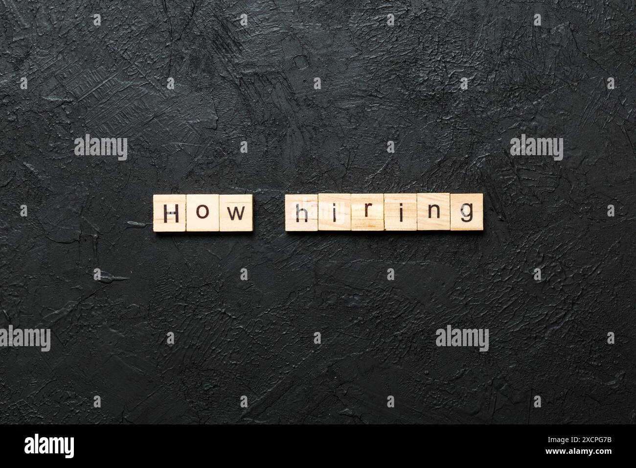 Now hiring word written on wood block. Now hiring text on cement table ...