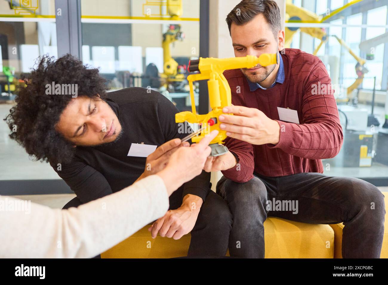 Two engineers closely inspecting a robotic arm model during a technical training session focused ...