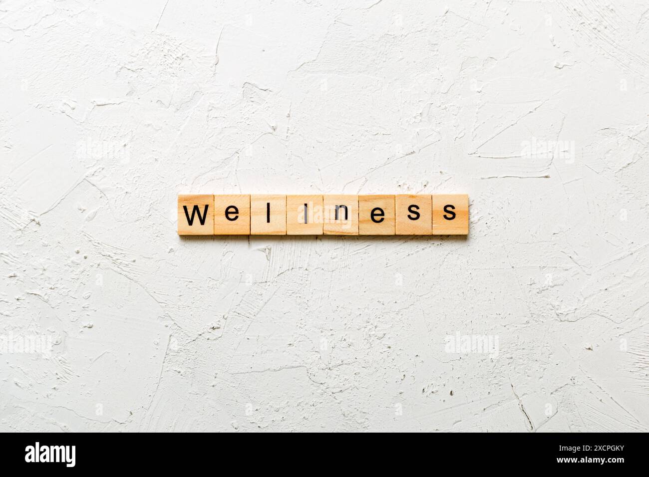 Wellness word written on wood block. Wellness text on cement table for ...