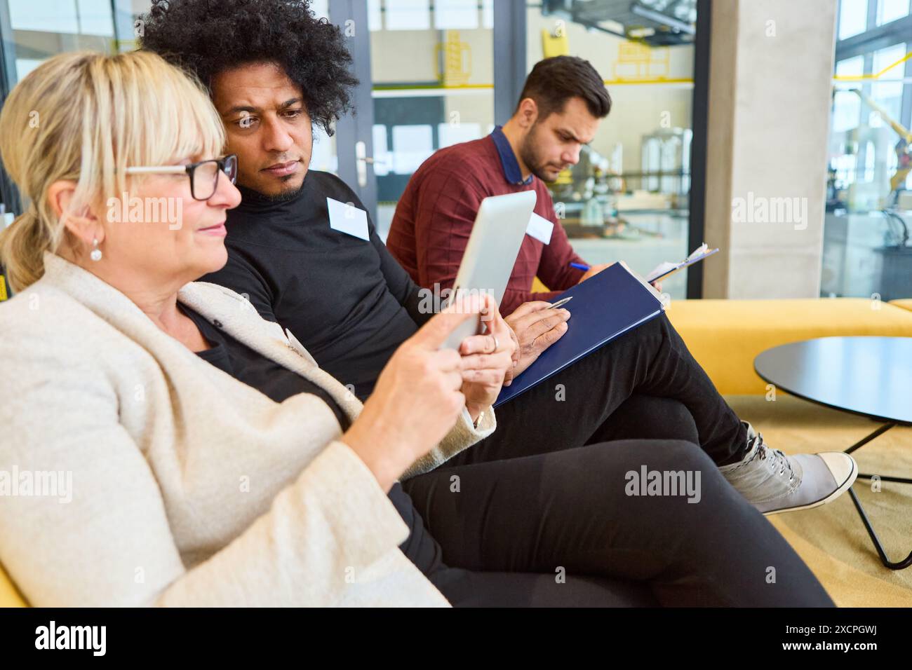 Diverse group of professionals collaborating on a project using a tablet and documents in a ...
