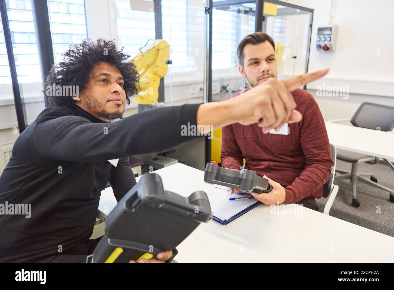 Two Engineers Collaborating On Robotics Training Working With Gripper Arm Controllers In An