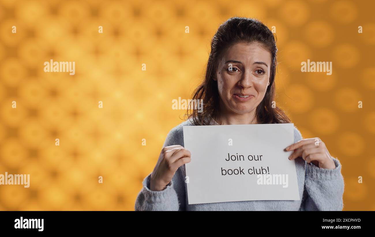 Cheerful book club president holds message urging people to join them ...