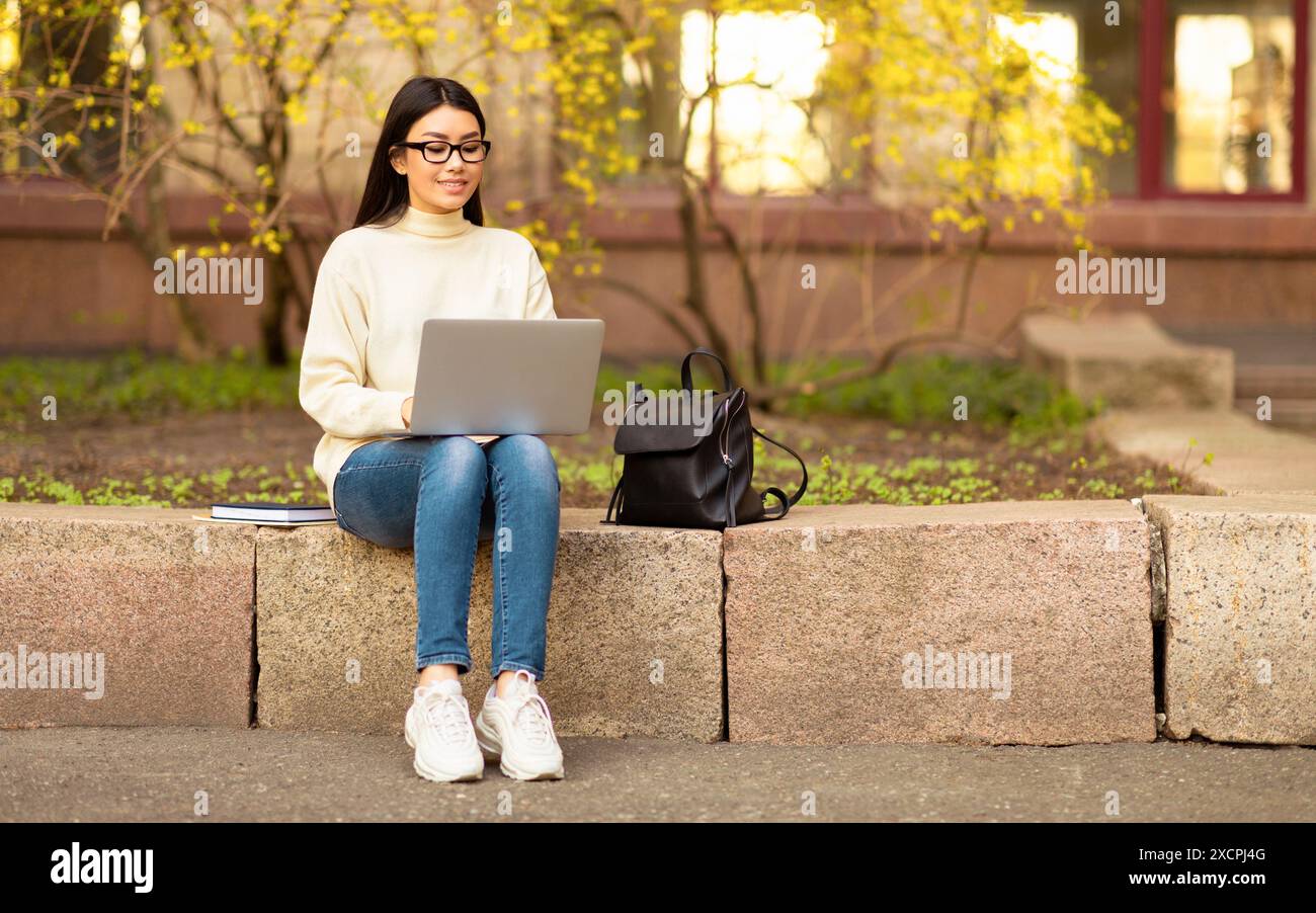 Woman Sitting on Ledge With Laptop, Studying Stock Photo - Alamy