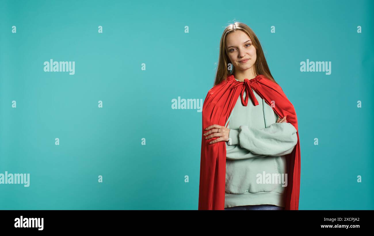 Smiling teenager portraying superhero wearing red cape, isolated over ...