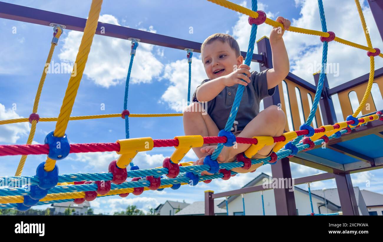 View from the ground on toddler boy walking over the rope bridge at ...