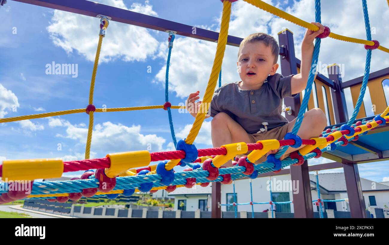 View from the ground on toddler boy walking over the rope bridge at ...