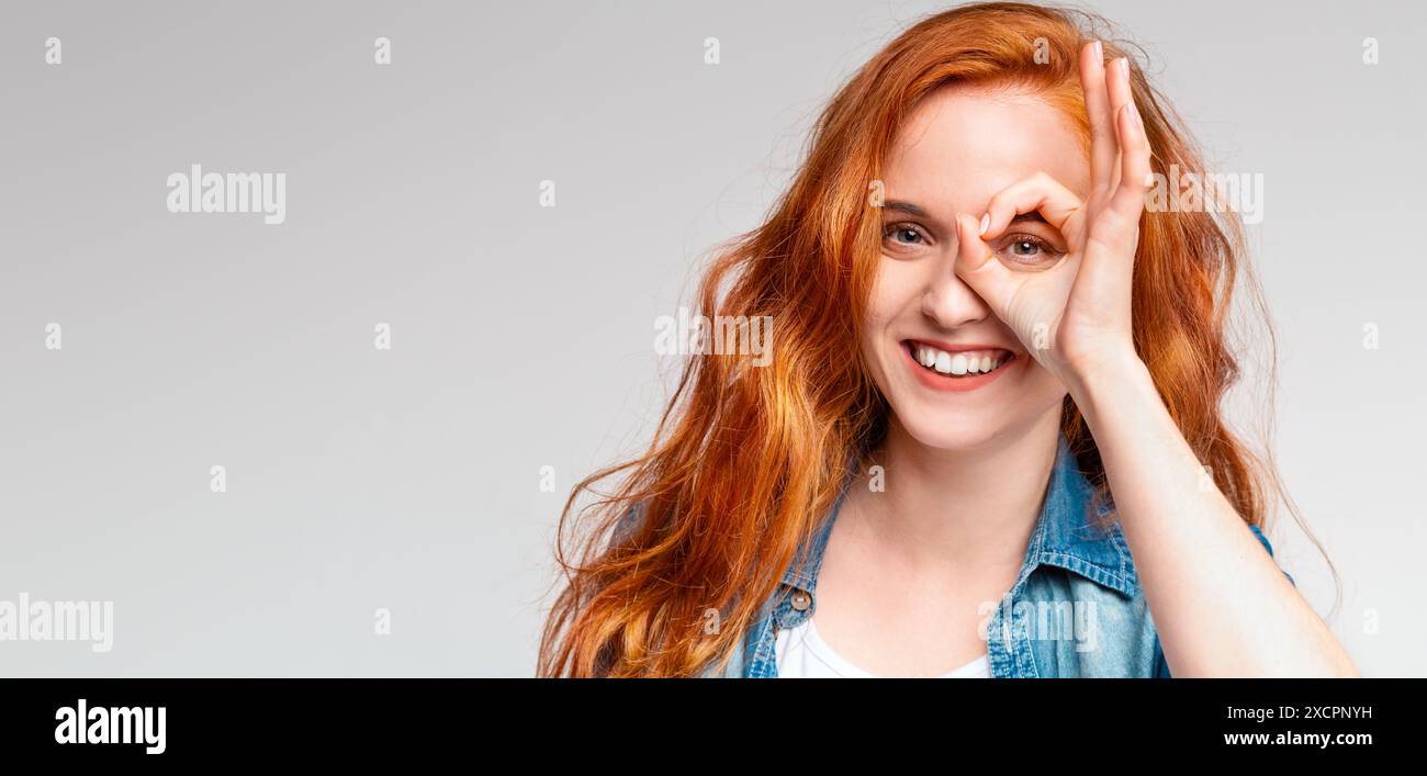Red-Haired Woman in Denim Jacket Making OK Sign Over Eye Stock Photo ...