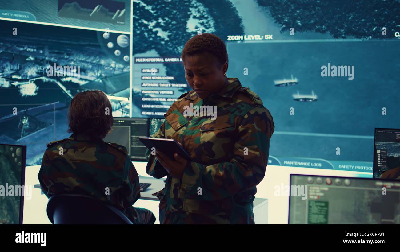 Female military officer supervising radar surveillance footage to input ...