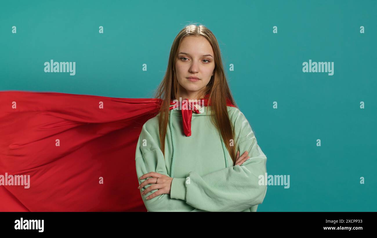 Happy young girl portraying superhero flying with cape fluttering in ...