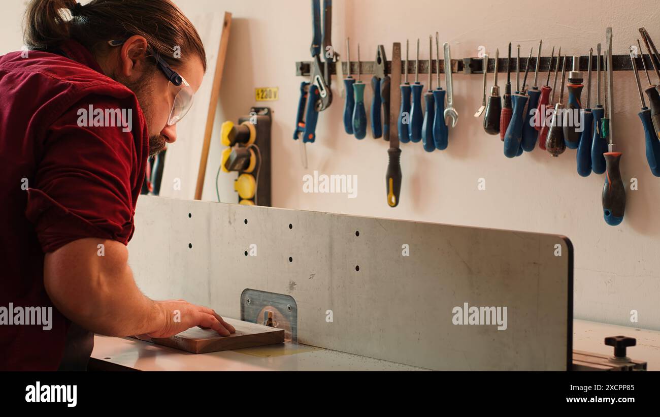Man putting on protection gear while inserting plank in spindle moulder ...