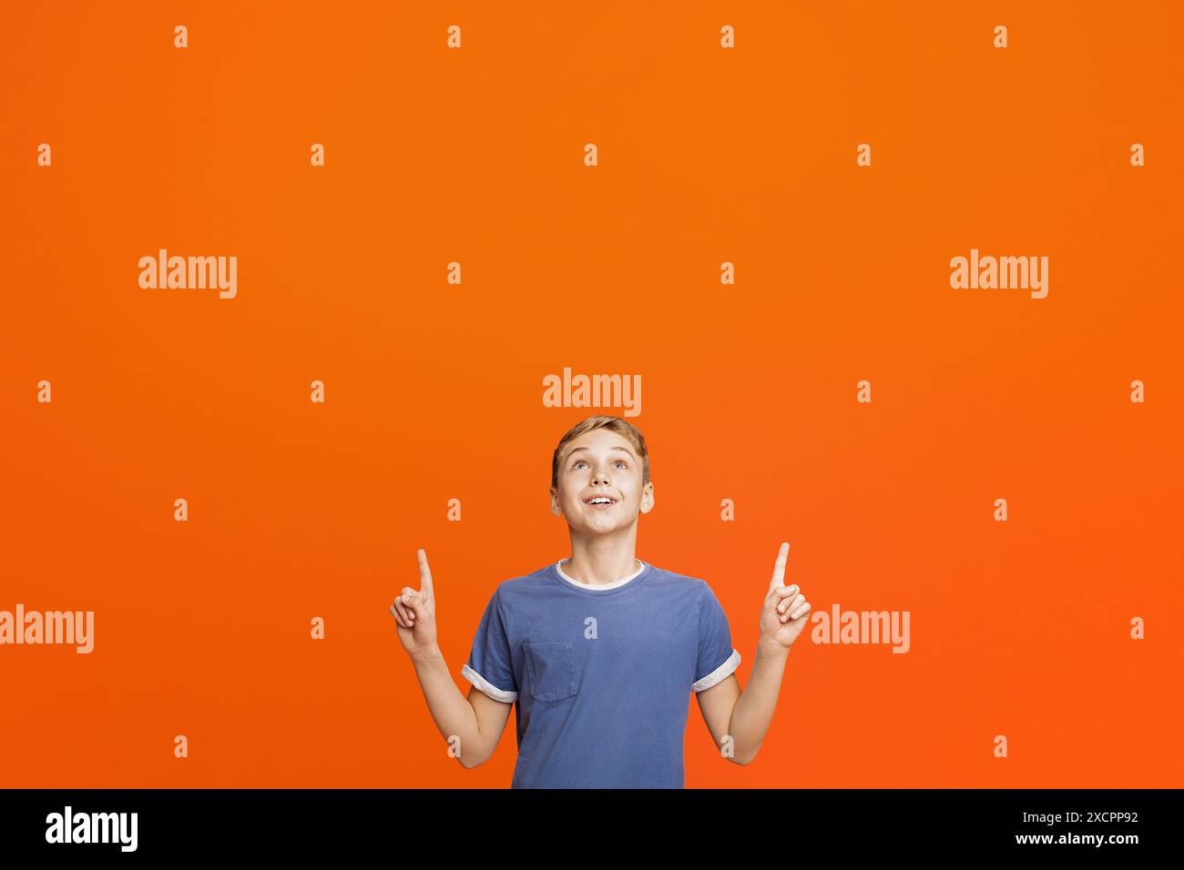 Cute little boy pointing up on orange background Stock Photo - Alamy