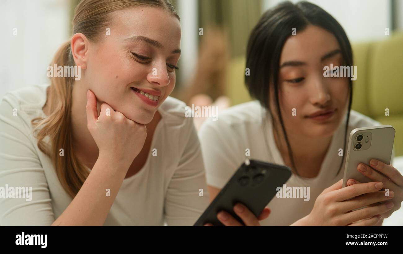 Two happy smiling multiracial friends multiethnic women diversity girls female Caucasian Asian ...