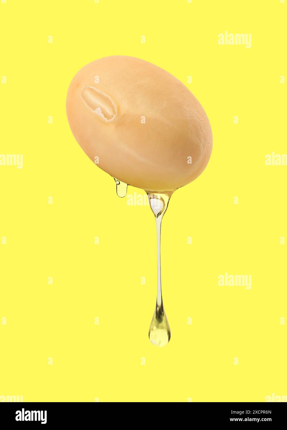Cooking oil dripping from soybean on yellow background Stock Photo - Alamy