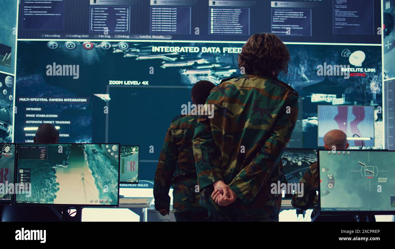 Military surveillance officers talking next to a big screen in general ...