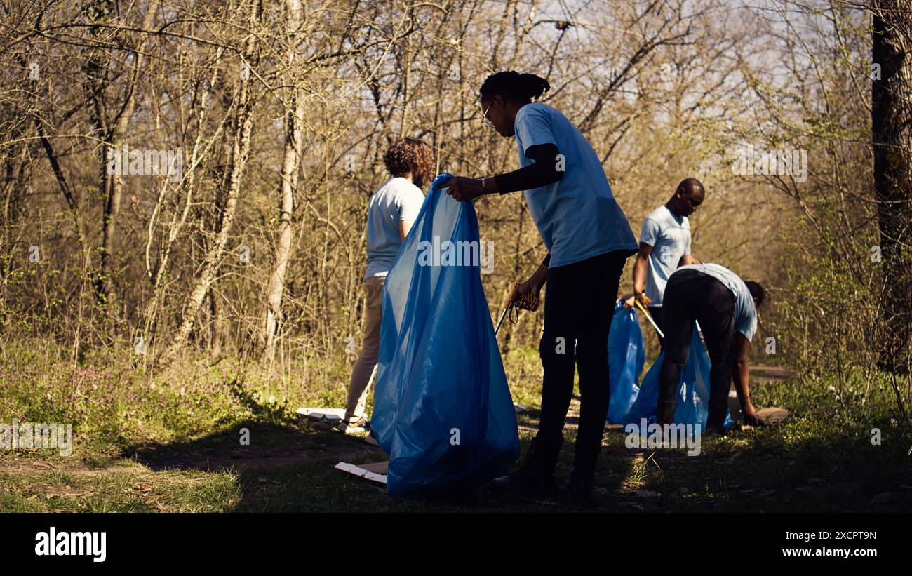 African american girl picking up trash with a long claw and garbage ...