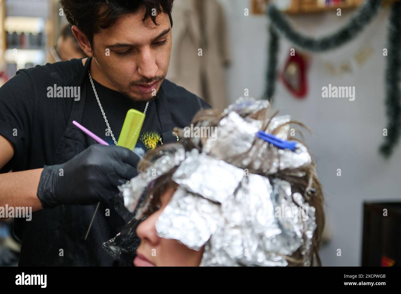Hairdresser applying highlights to client's hair at a beauty salon ...