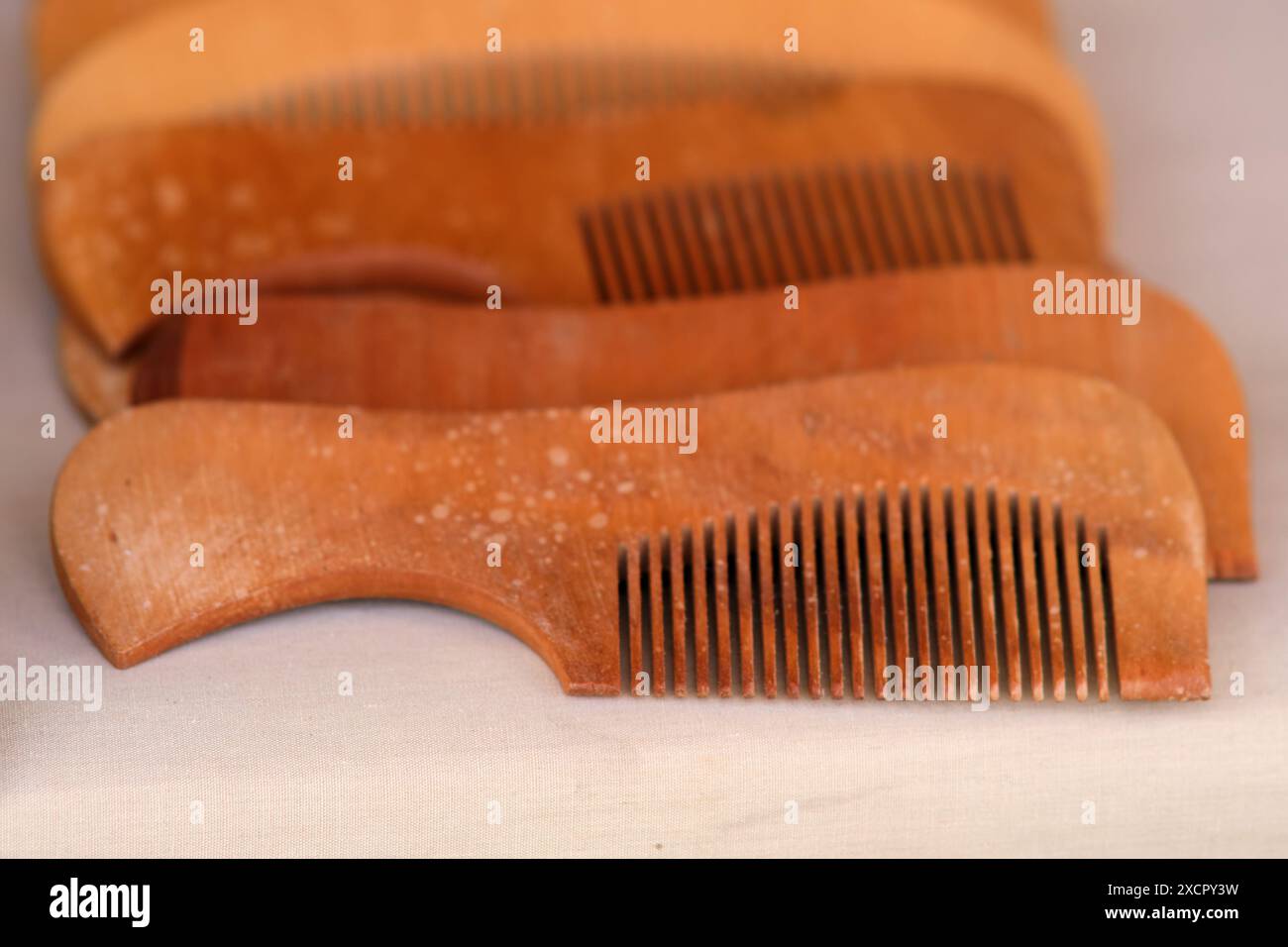 A row of wooden combs are lined up on a table. The combs are all ...