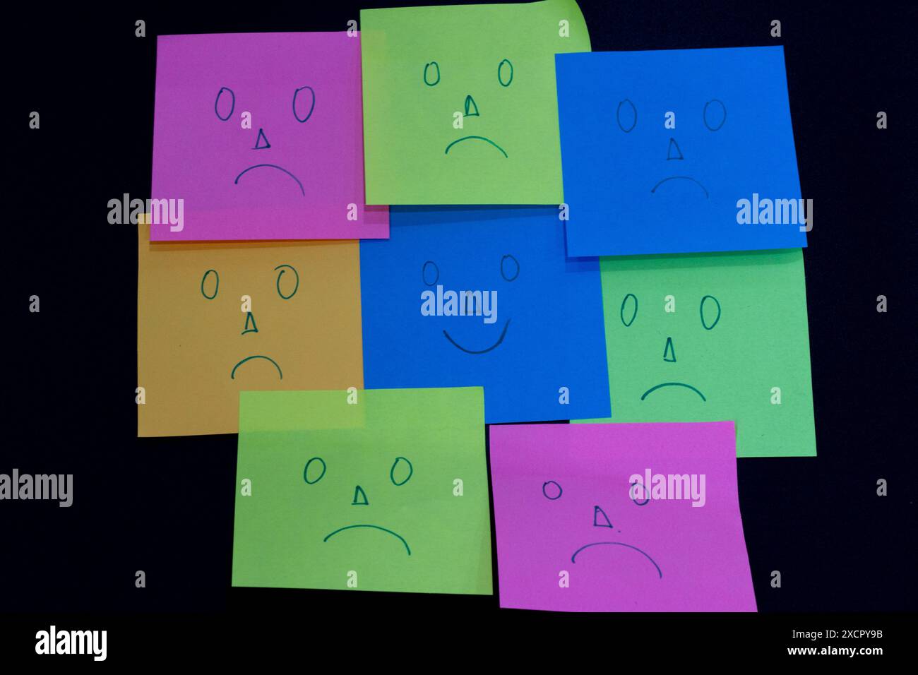 One smiley face amongst all the sad faces drawn on sticky notes Stock ...