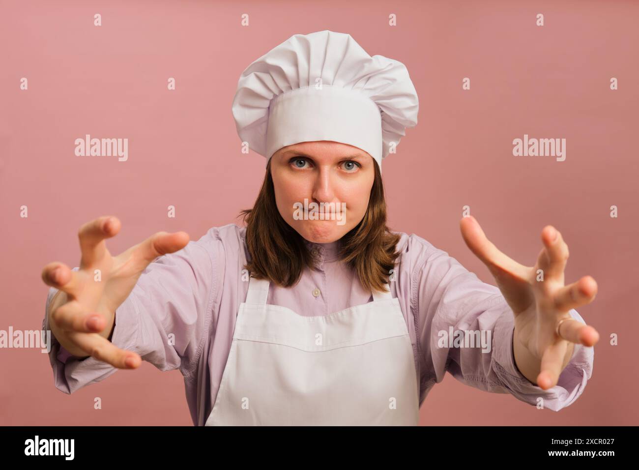 Woman cook stretching her arms on studio pink background. Portrait of a ...
