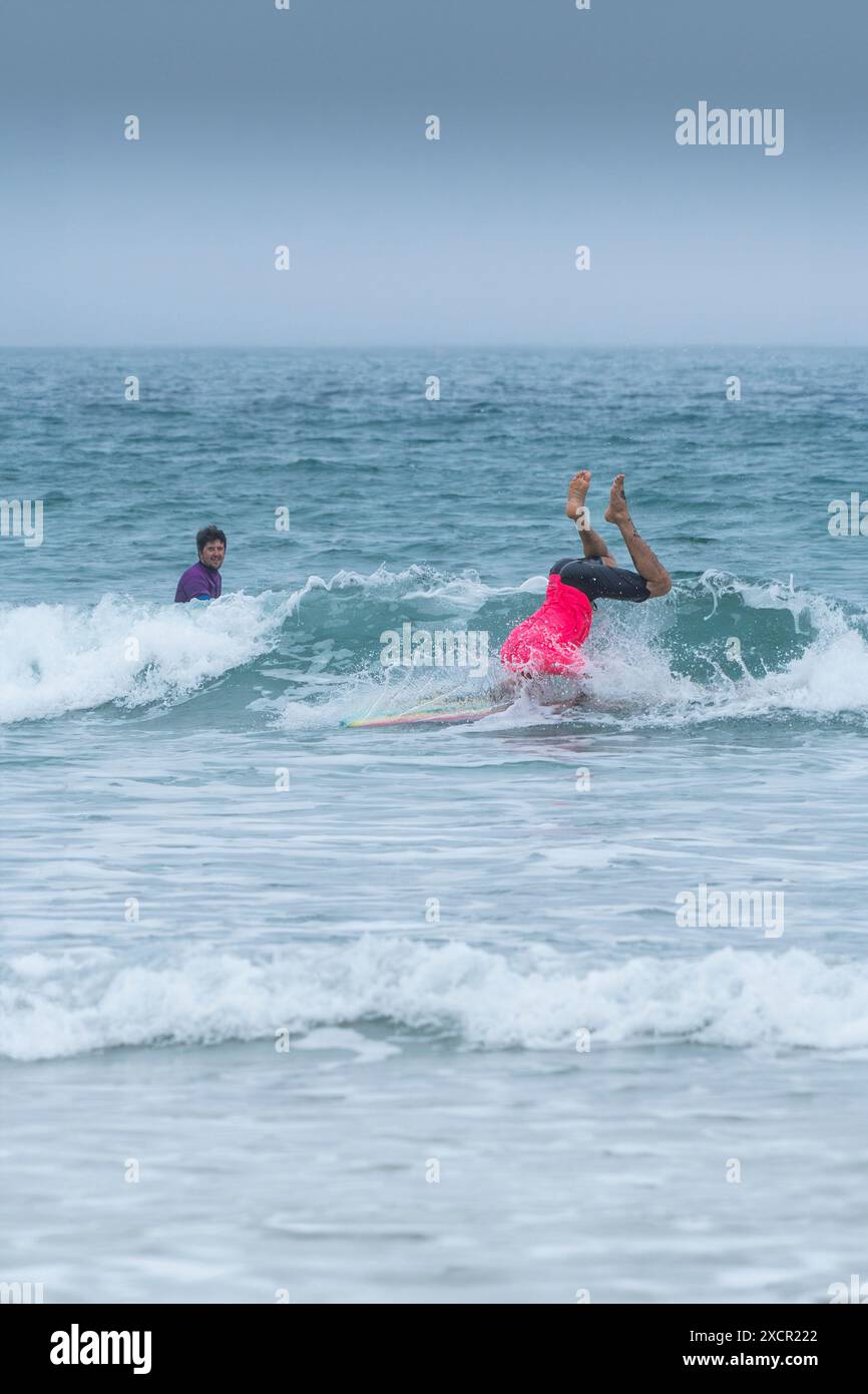An enthusiastic surfer attempting a handstand on his surfboard in the ...