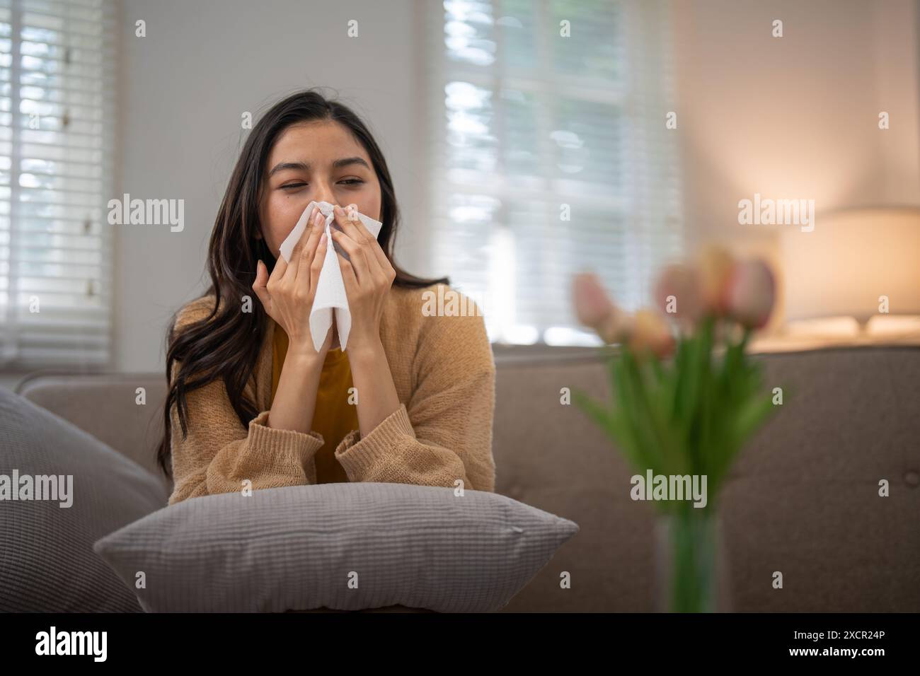 Woman sneezing due to pollen allergy at home. Concept of seasonal ...
