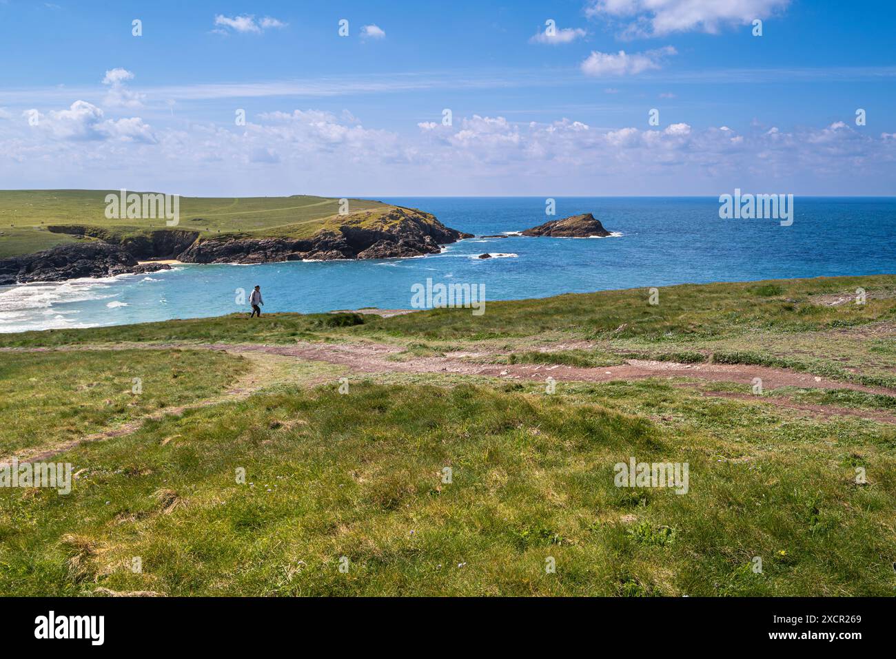 A walker on the South West Coast path overlooking Porth Joke Polly Joke ...