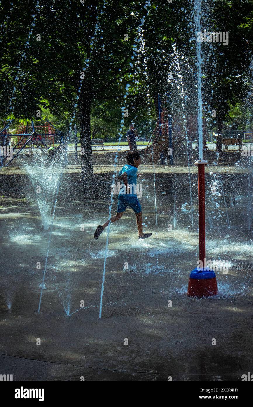 A kids running trough the water jet at the play fountains park Stock ...