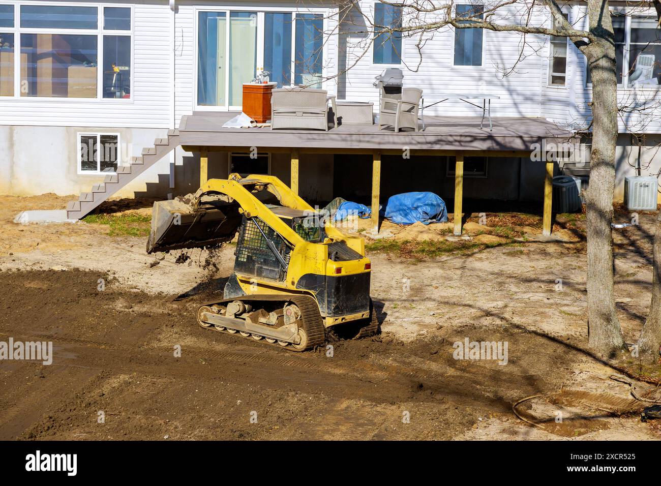 At earthmoving site, tractor is leveling ground during work on backyard ...