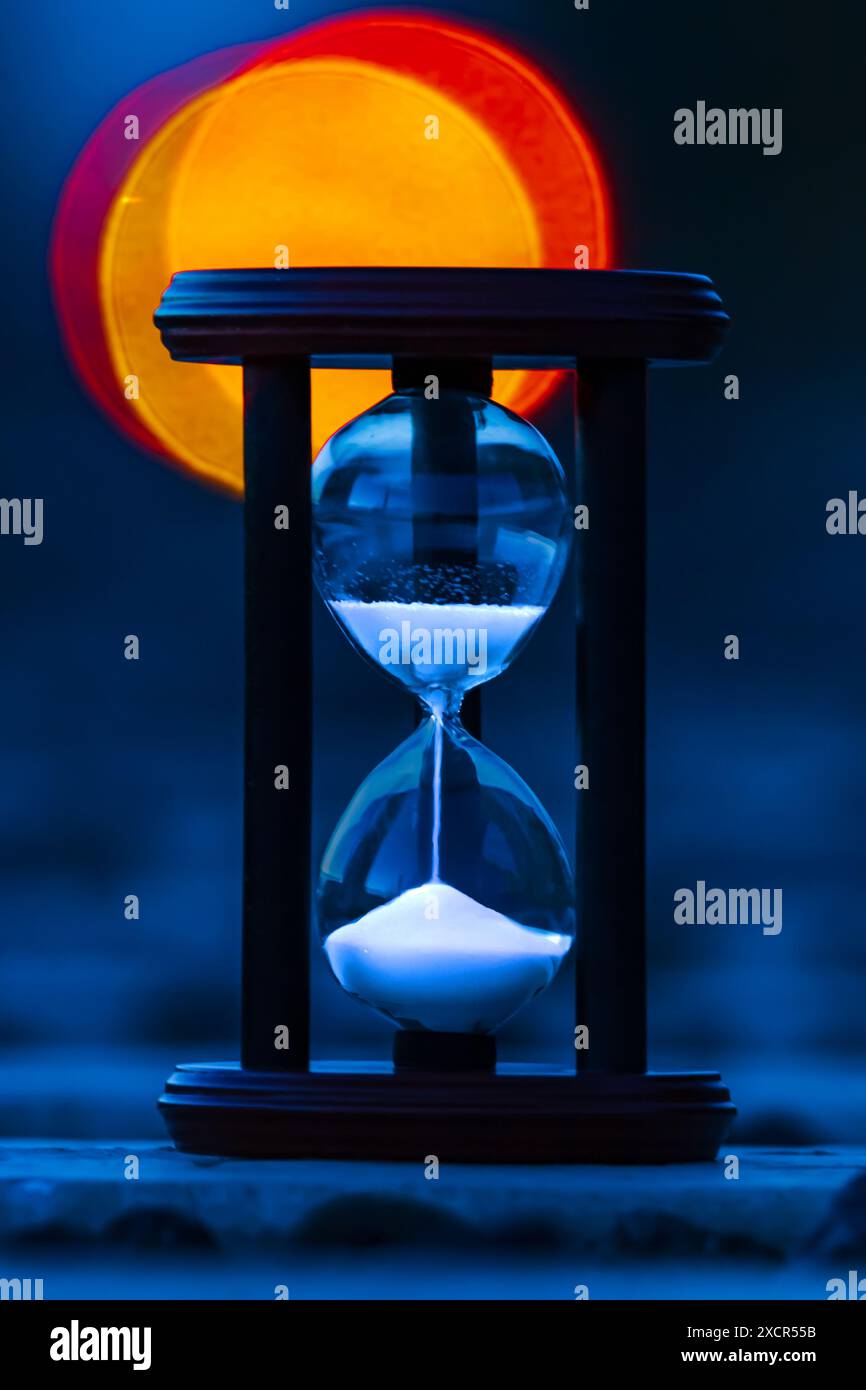 Hourglass with falling sand against blurred colorful lights Stock Photo ...