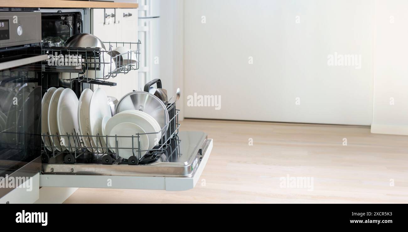 Open built-in dishwasher machine with clean cutlery, dishes, plates in ...