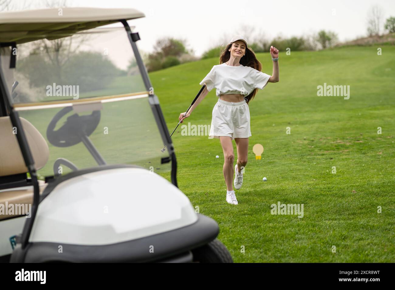 Active woman standing by the vehicle with golf in nature Stock Photo ...