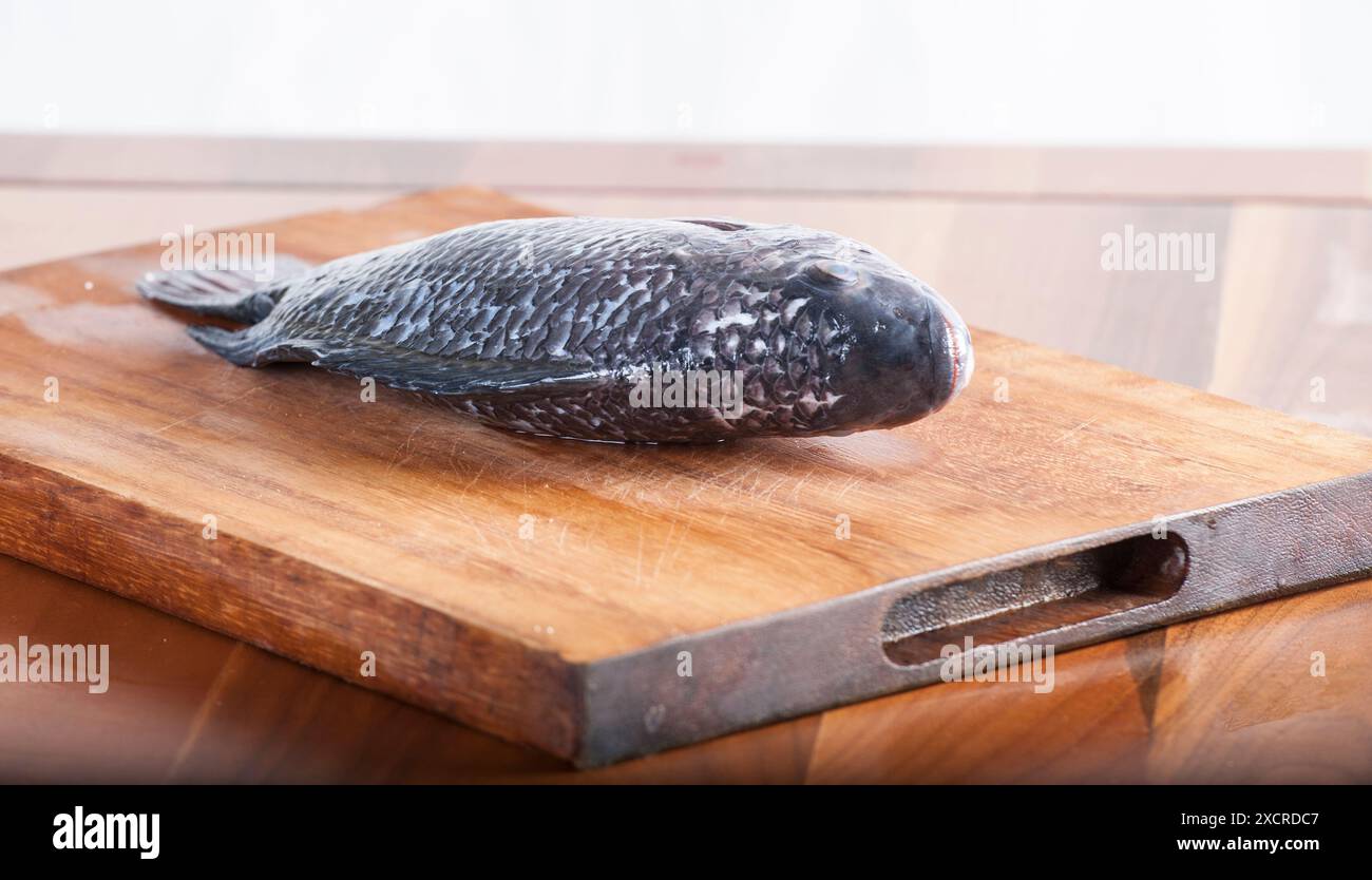 raw tilapia fish on a cutting board Stock Photo - Alamy