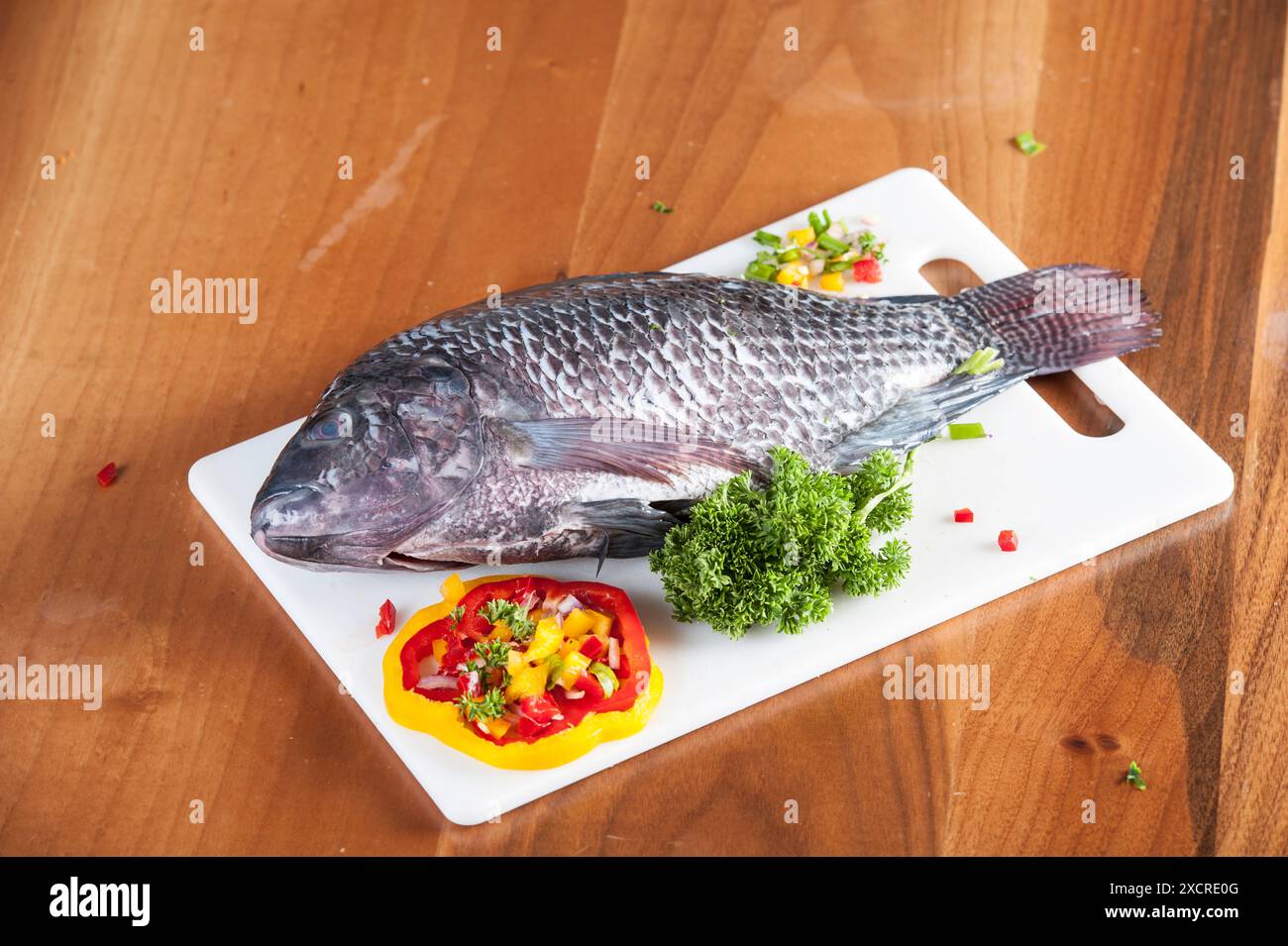 raw tilapia fish on a cutting board Stock Photo - Alamy