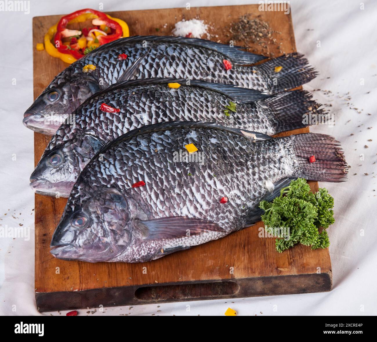 raw tilapia fish on a cutting board Stock Photo - Alamy