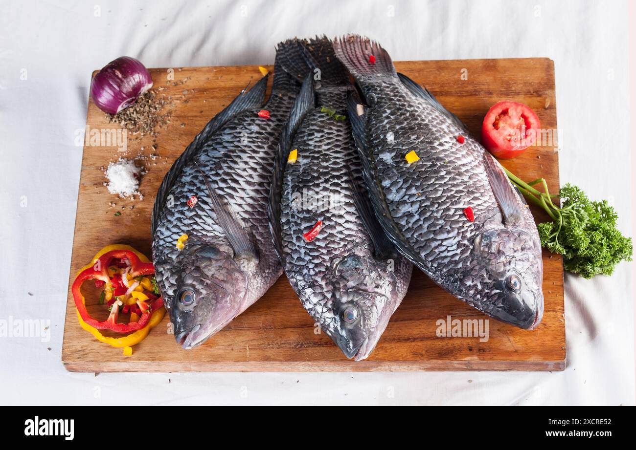 raw tilapia fish on a cutting board Stock Photo - Alamy