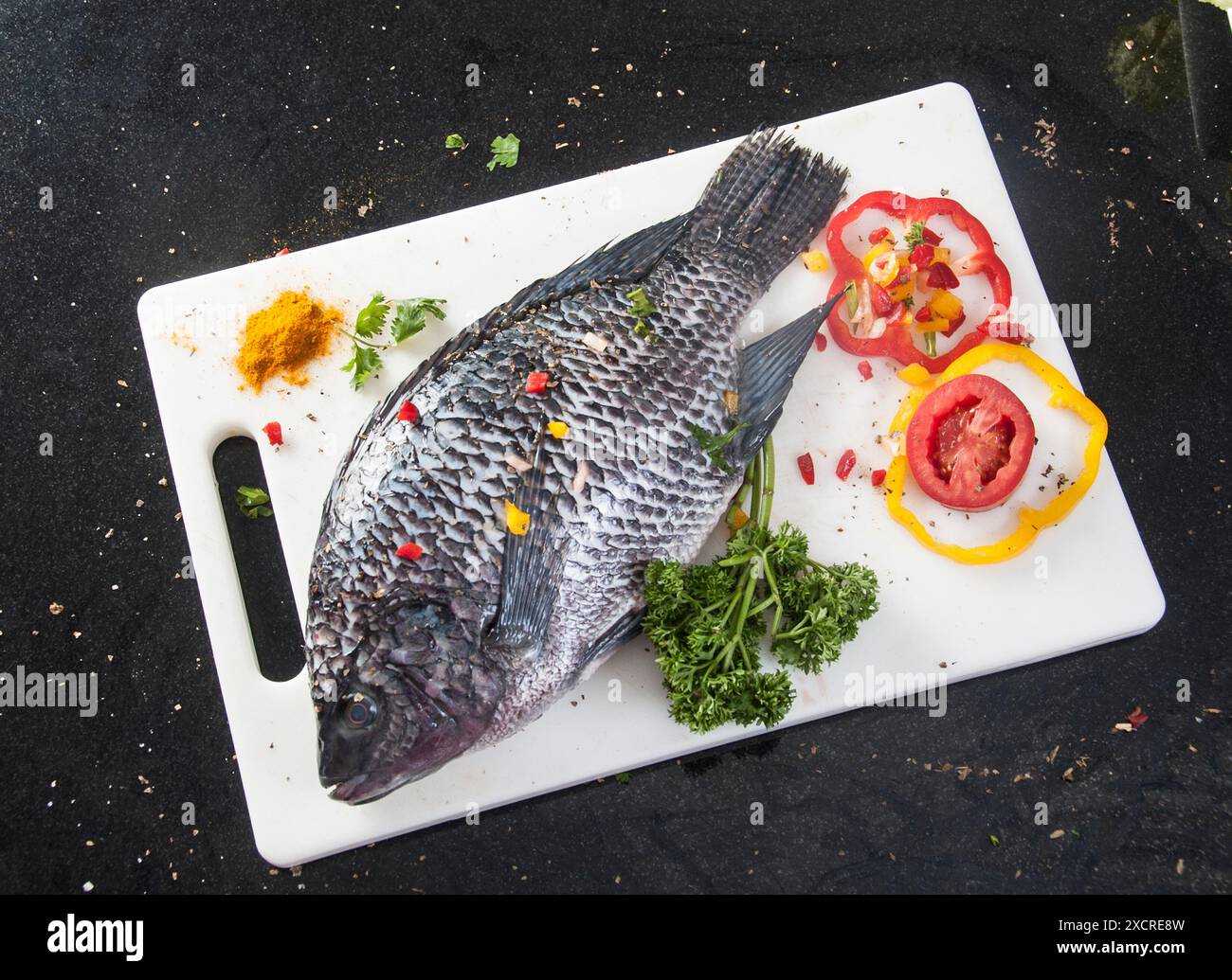 raw tilapia fish on a cutting board Stock Photo - Alamy