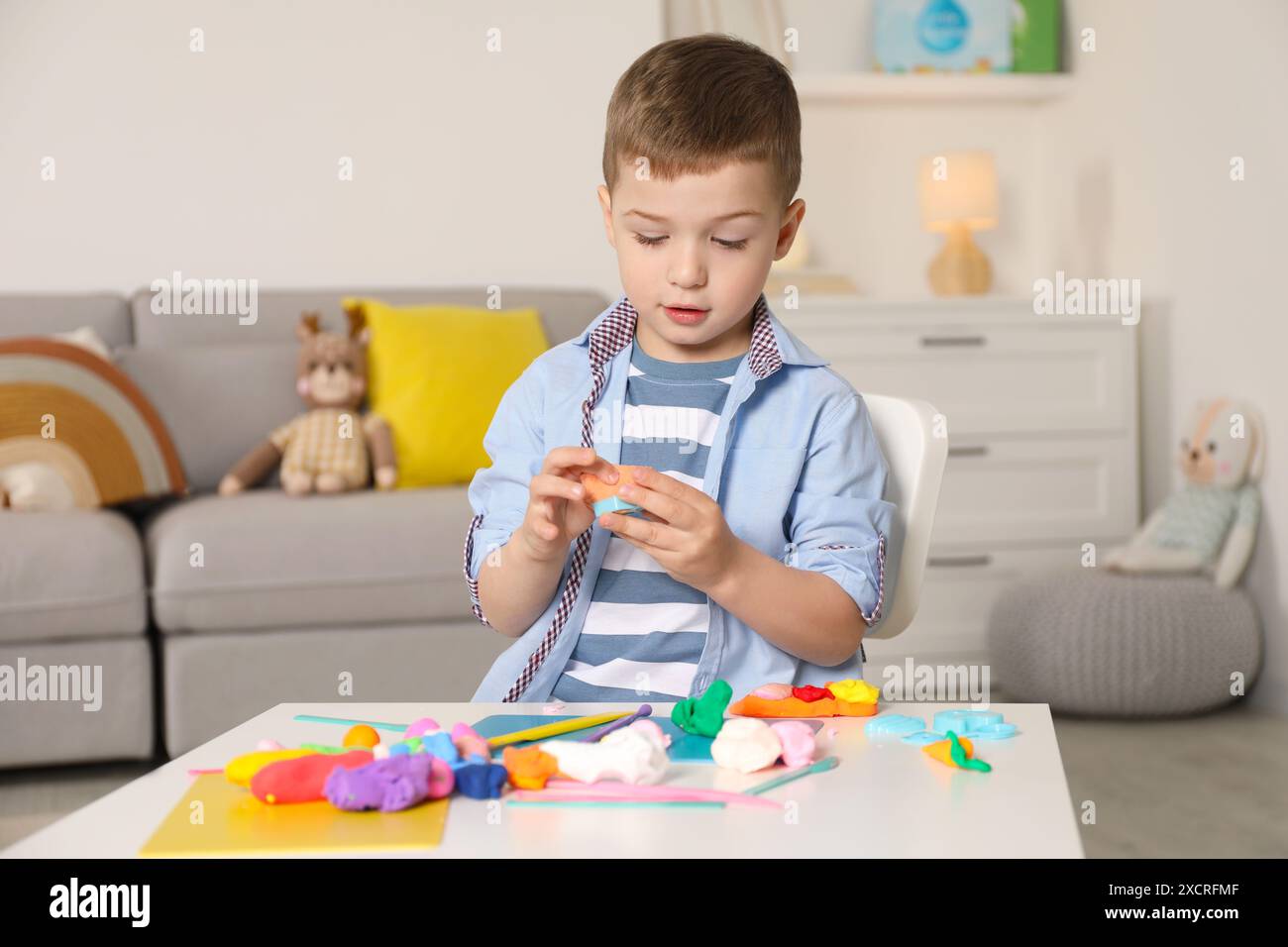 Little boy sculpting with play dough at table in kindergarten Stock ...