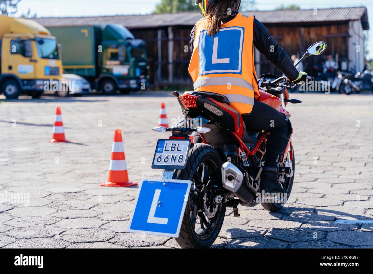 A woman in a reflective vest is riding a motorcycle. She is wearing a ...