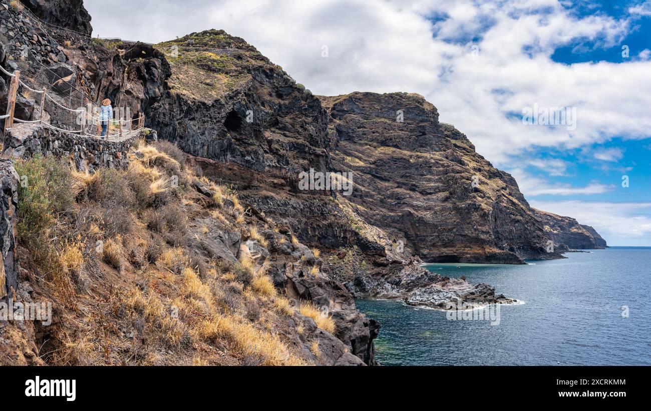 Female tourist climbing a steep cliffside trail on the island of La ...